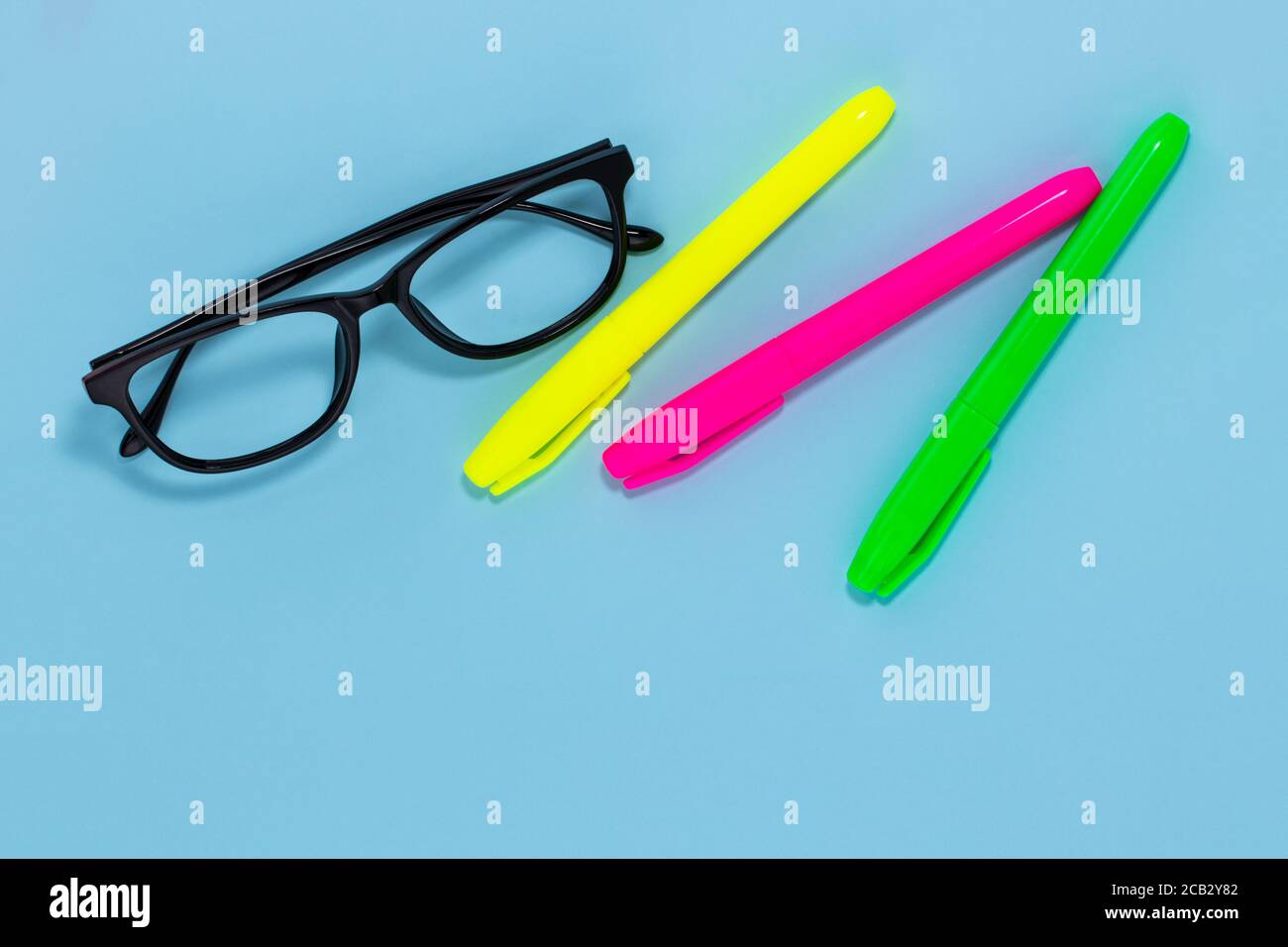 Education concept. Glasses and three markers on a blue background with ...