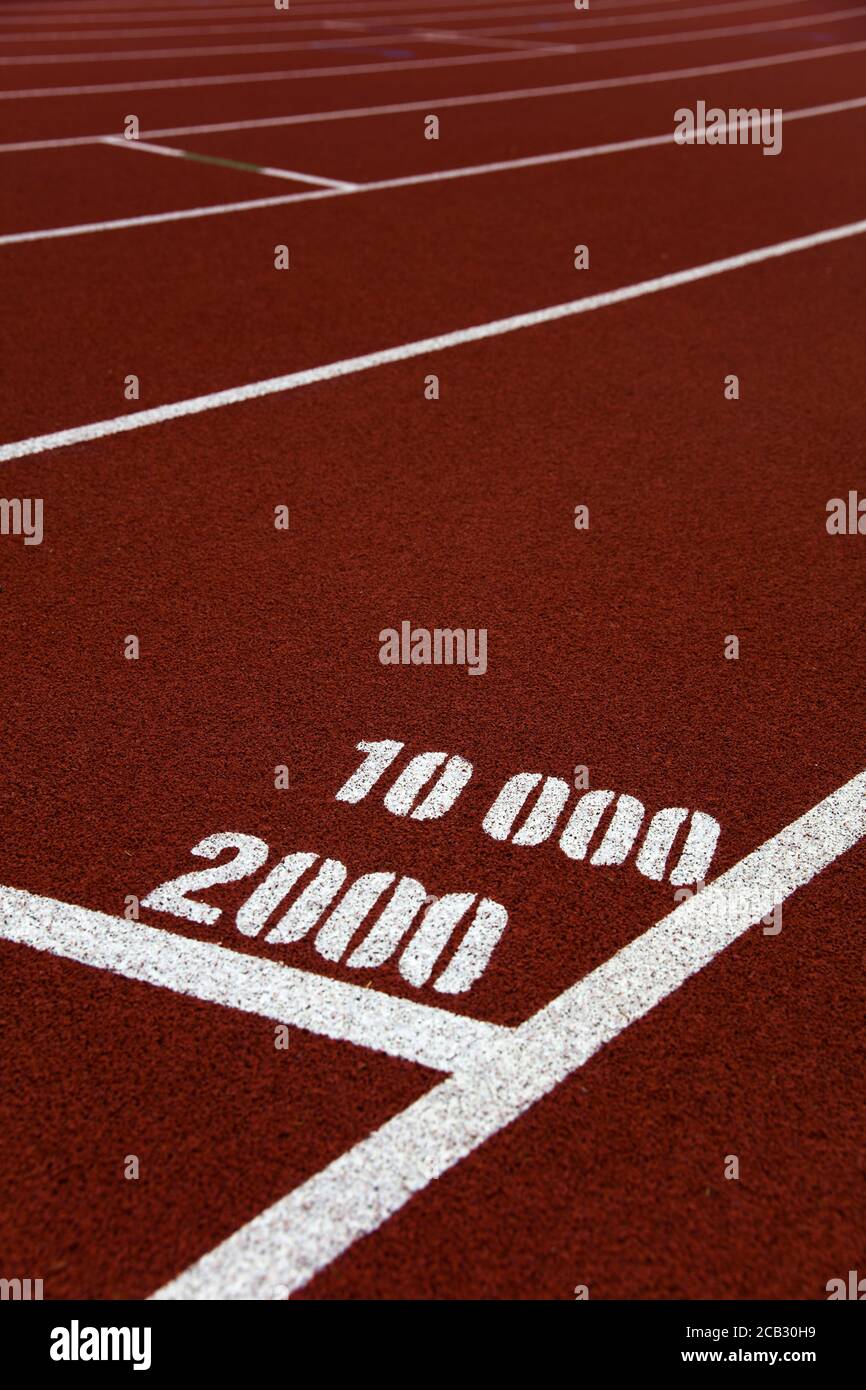 Closeup of the 2000 and 10000 meters marks on red stadium running track ...