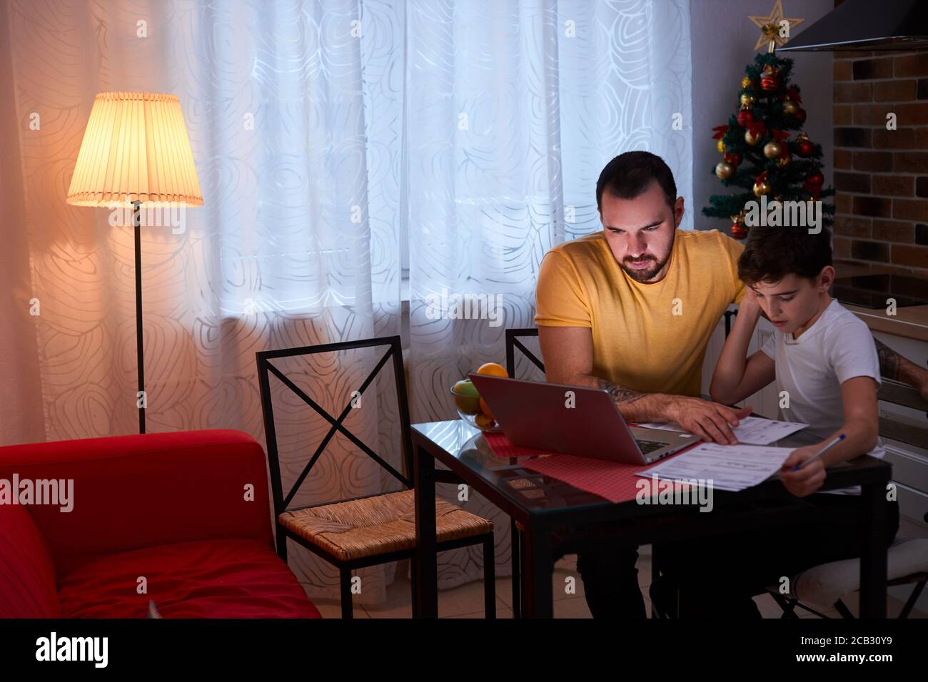 careful father help his diligent son to do homework, to study at home ...