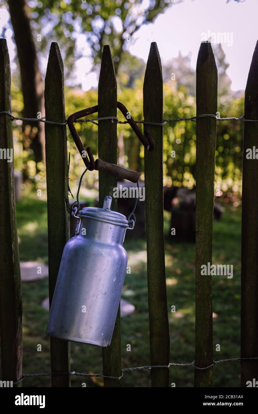 Milk pot hanging from a wooden fence Stock Photo - Alamy