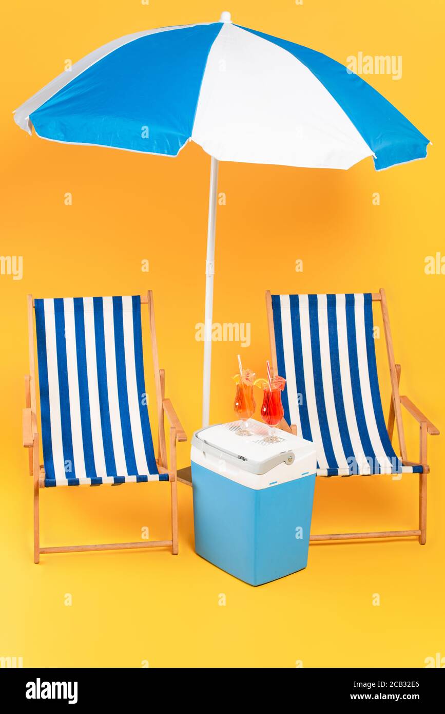 deck chair near beach umbrella and cocktails on portable fridge freezer ...