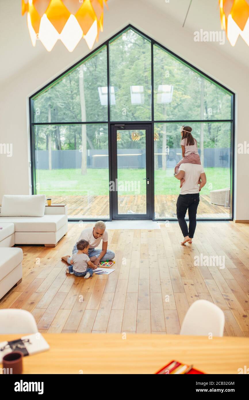 White interior of room, big panoramic windows. Family playing with each ...