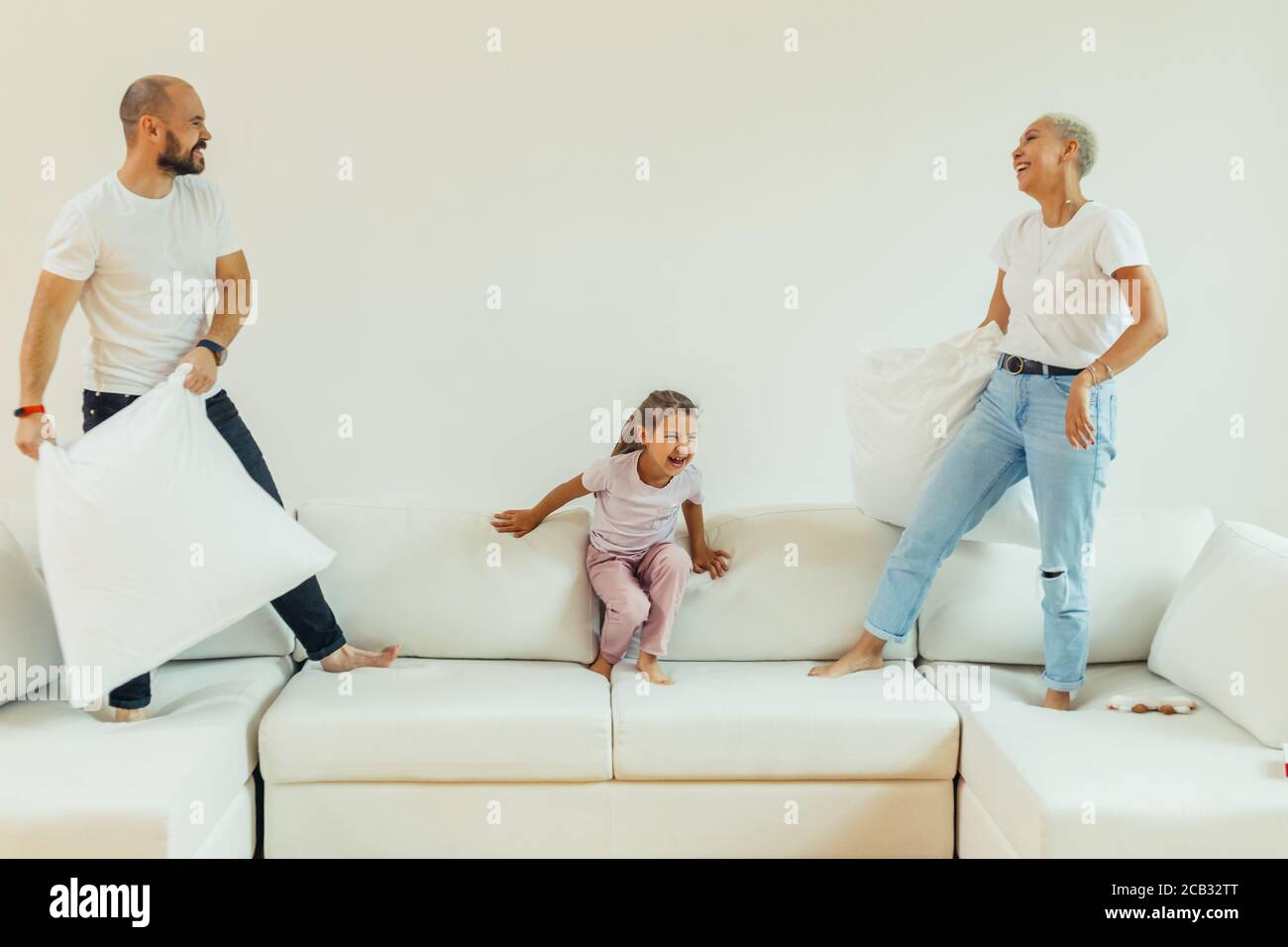 Happy joyful family fighting pillow battle on bed at home with children ...