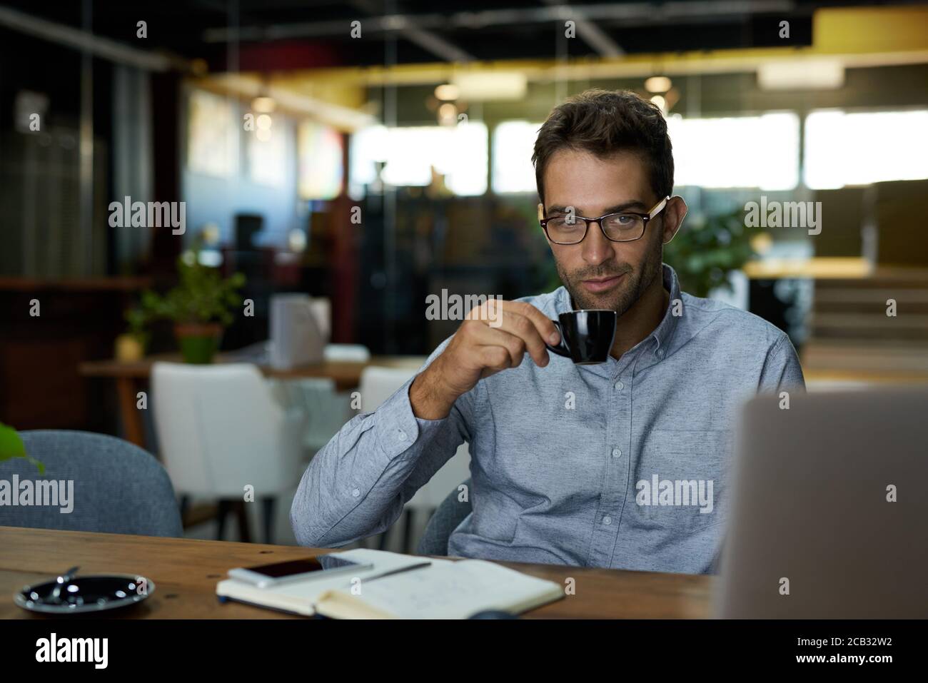 Young businessman drinking coffee at his office desk Stock Photo - Alamy