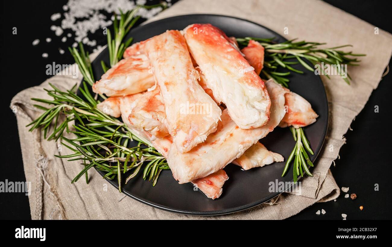Close-up king crab leg meat on a dark plate with spices and herbs ...