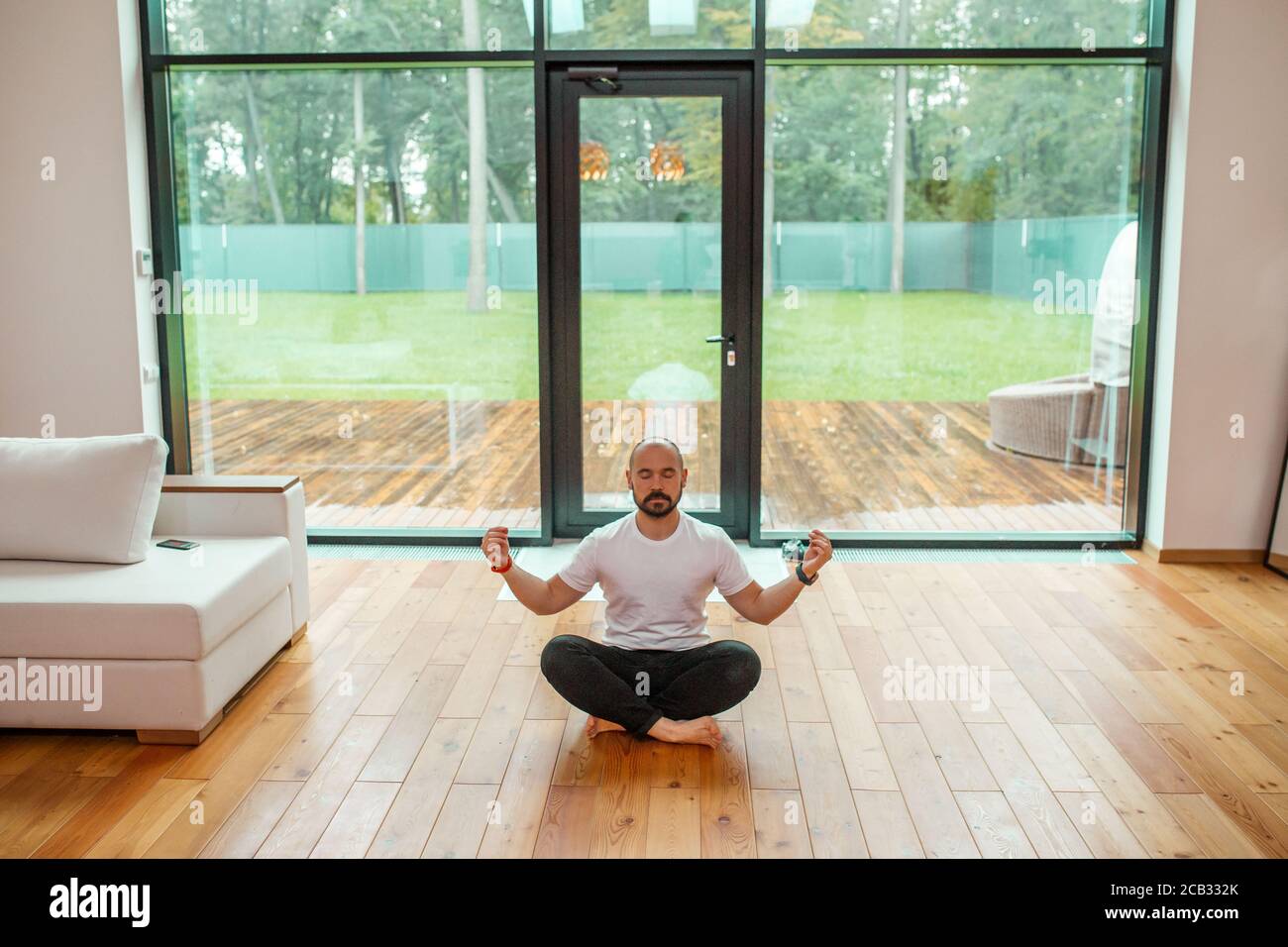 Male in casual clothes sit in lotus position meditate, relax in living ...