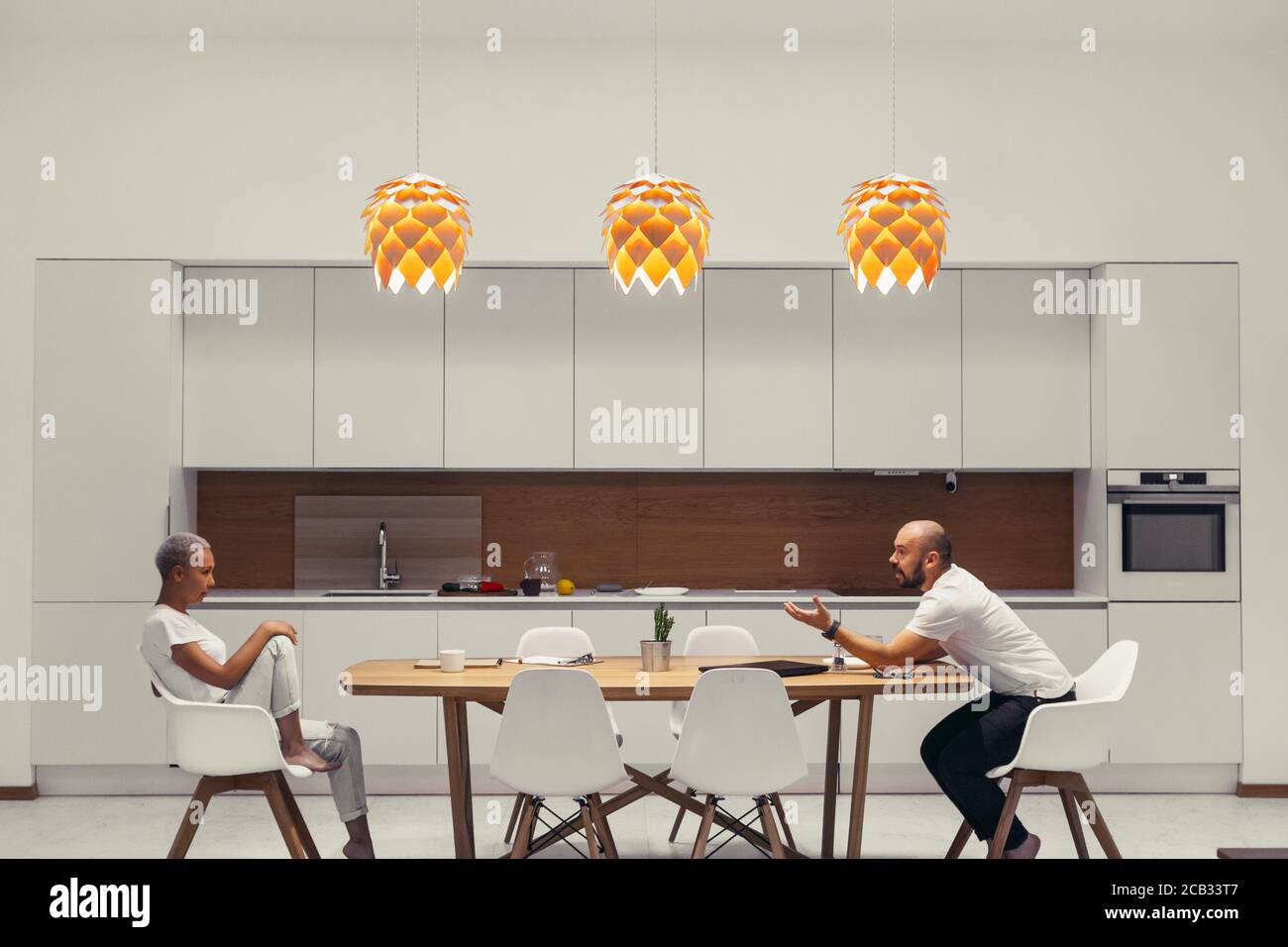 Family couple sit opposite one another at home on table and speak about ...