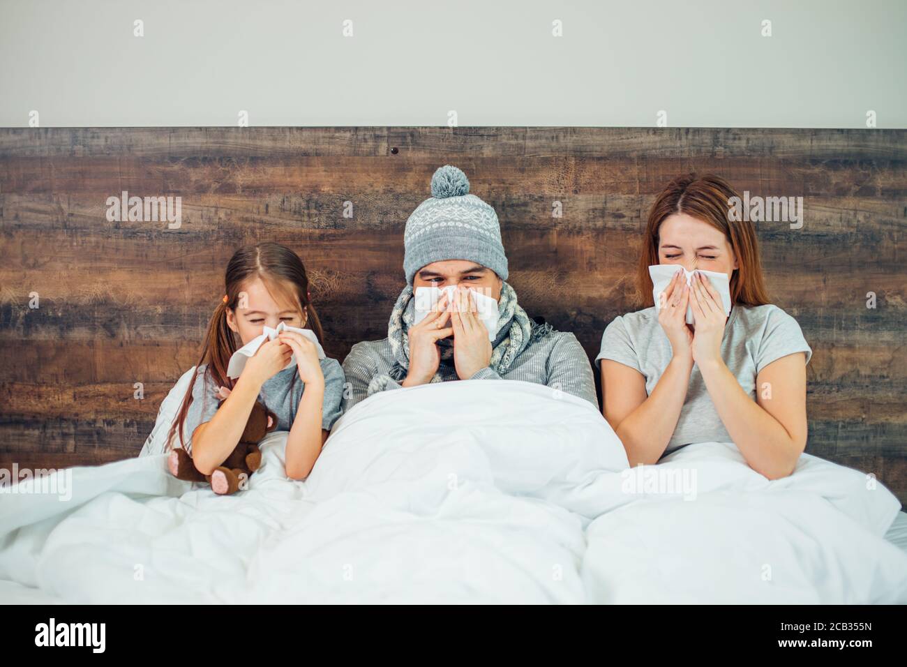 ill caucasian family lying on bed together, suffering from disease ...