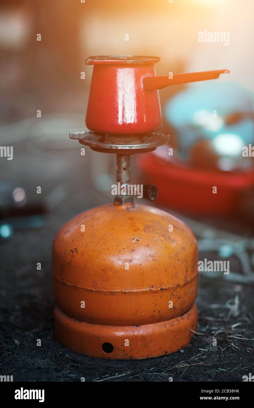 Orange camp gas canister with red coffee pot Stock Photo - Alamy