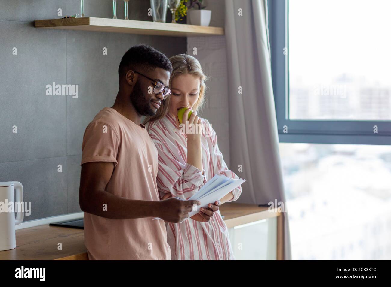 Young multi-ethnic couple stand at the kitchen, planning their joint ...