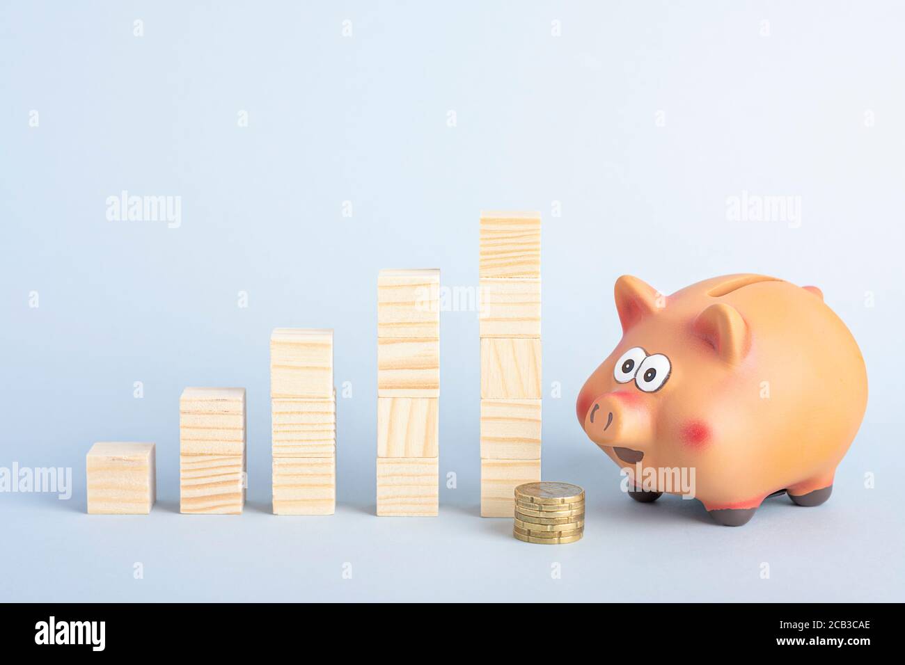 A piggy bank, coins and growth graph from wooden blocks Stock Photo - Alamy