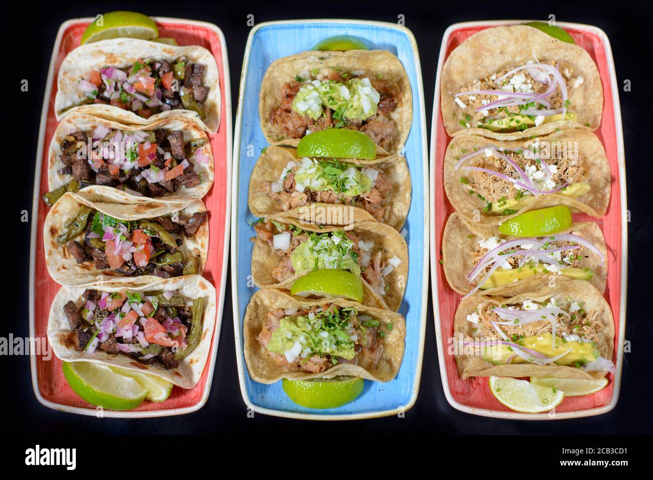 Three different plates with tacos on a black background Stock Photo - Alamy