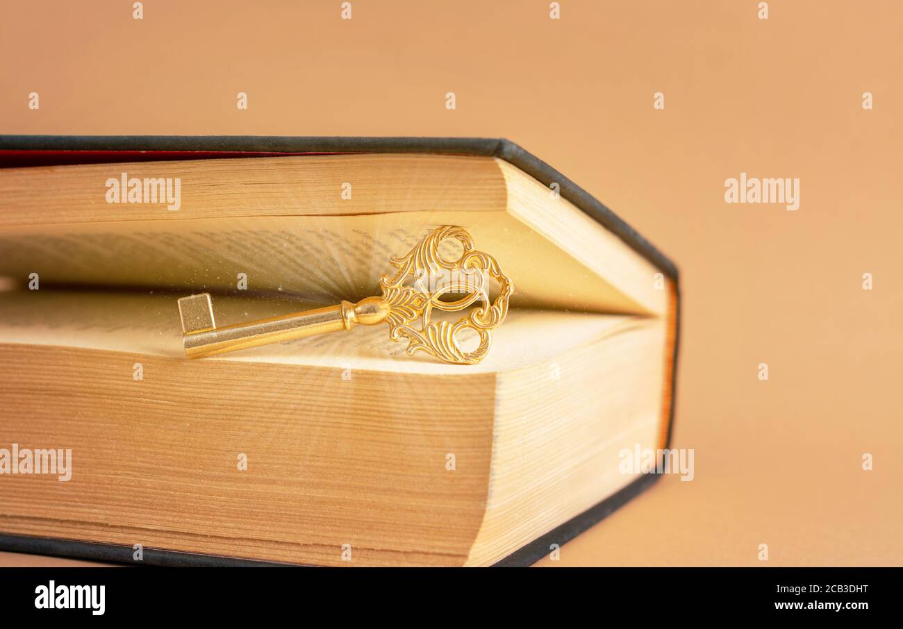 A old beautiful key with magic light lays between the pages of old book ...