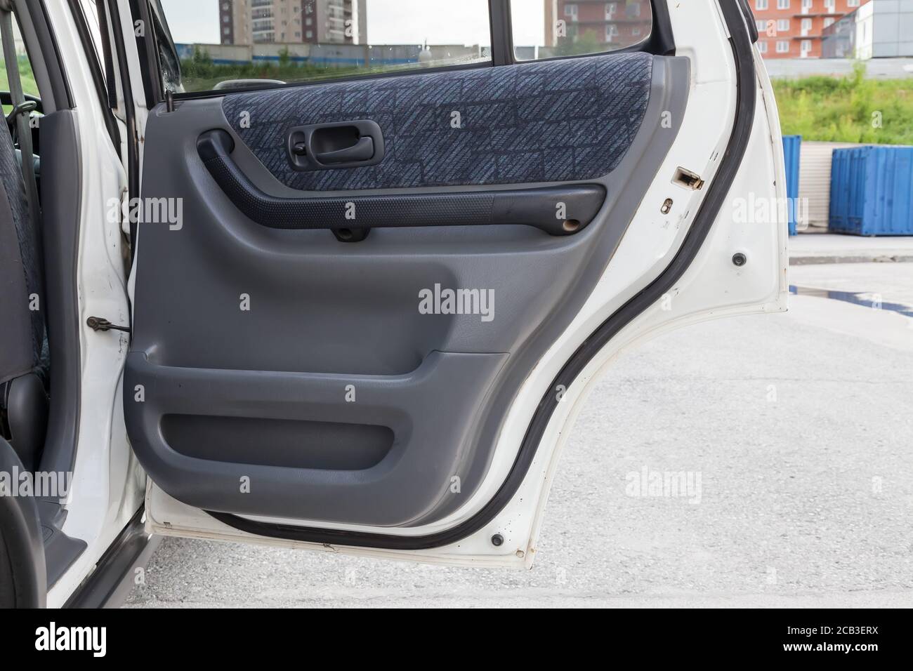 The open rear door of a Japanese car with black plastic trim and a gray ...