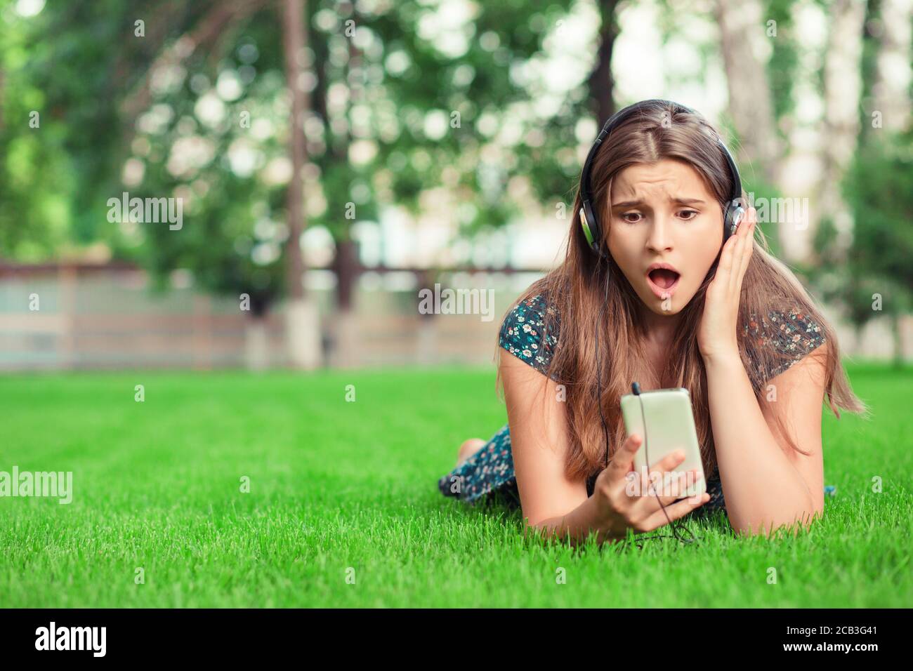 Surprised shocked young woman looking at phone seeing unexpected news ...