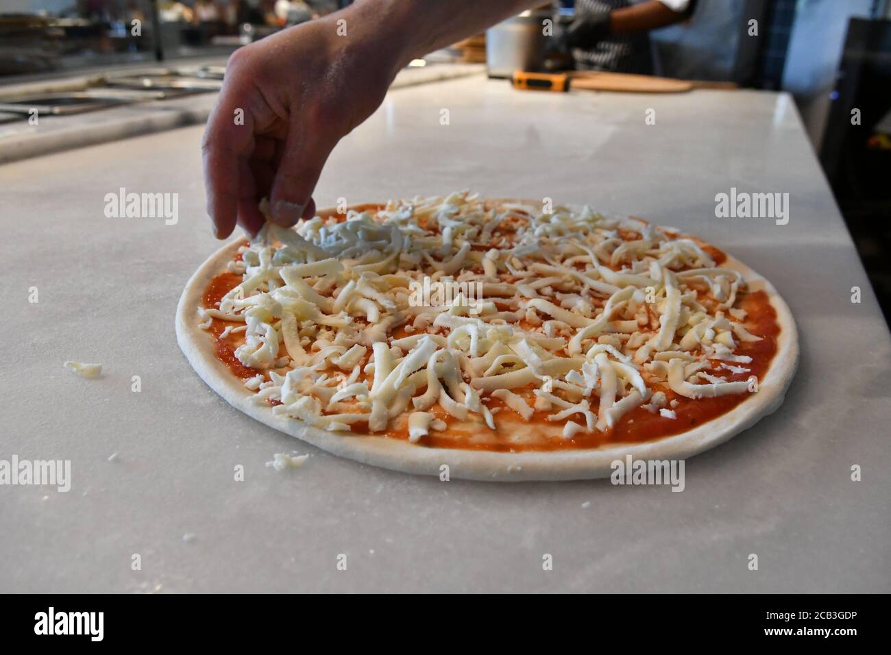 Professional chef making delicious pizza in a kitchen at a restaurant ...