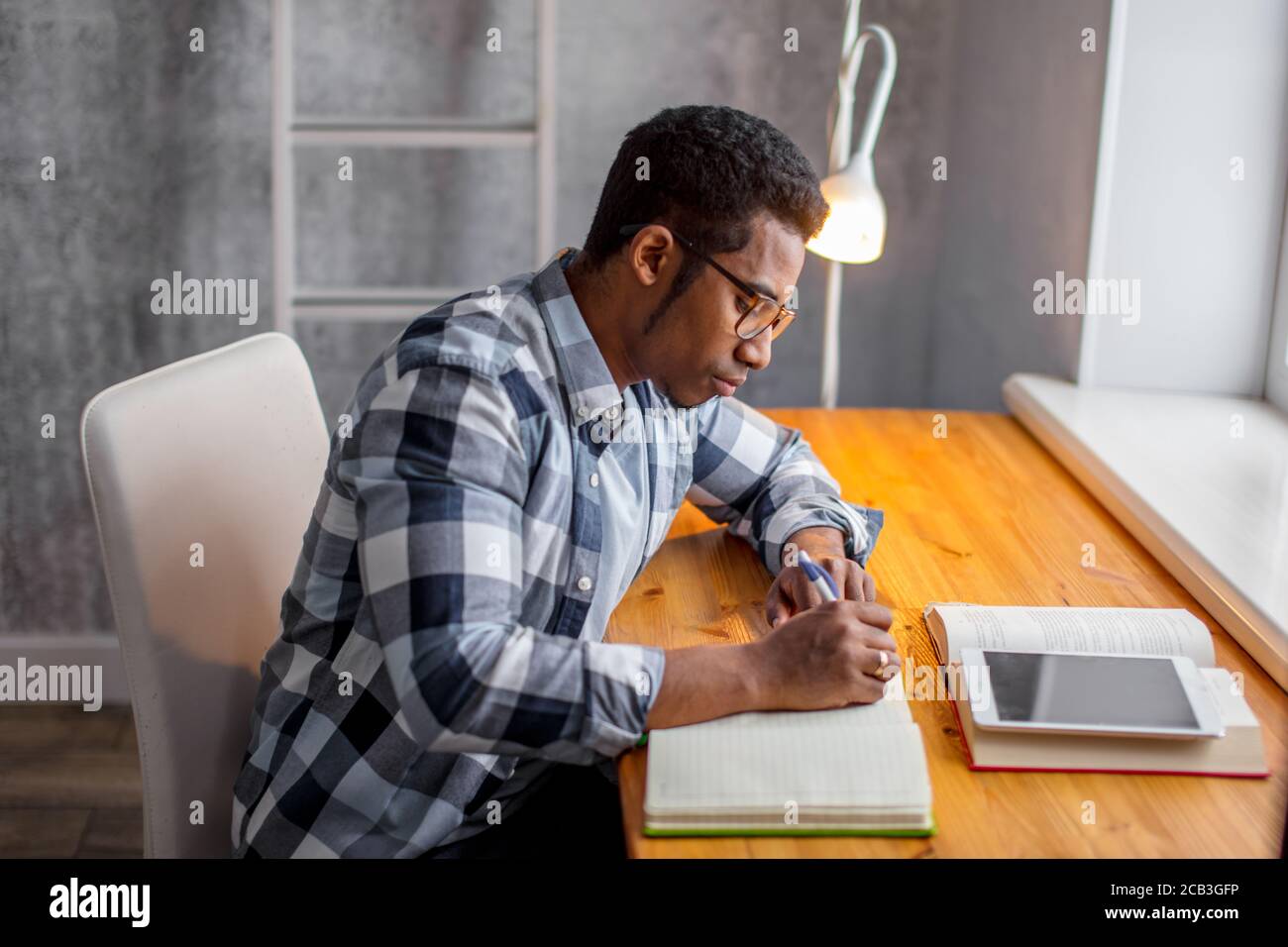 handsome serious African guy making notes in the bedroom, close up side ...
