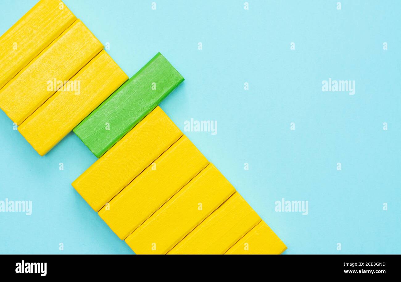 Yellow and green block of jenga block on blue background. Out of the ...