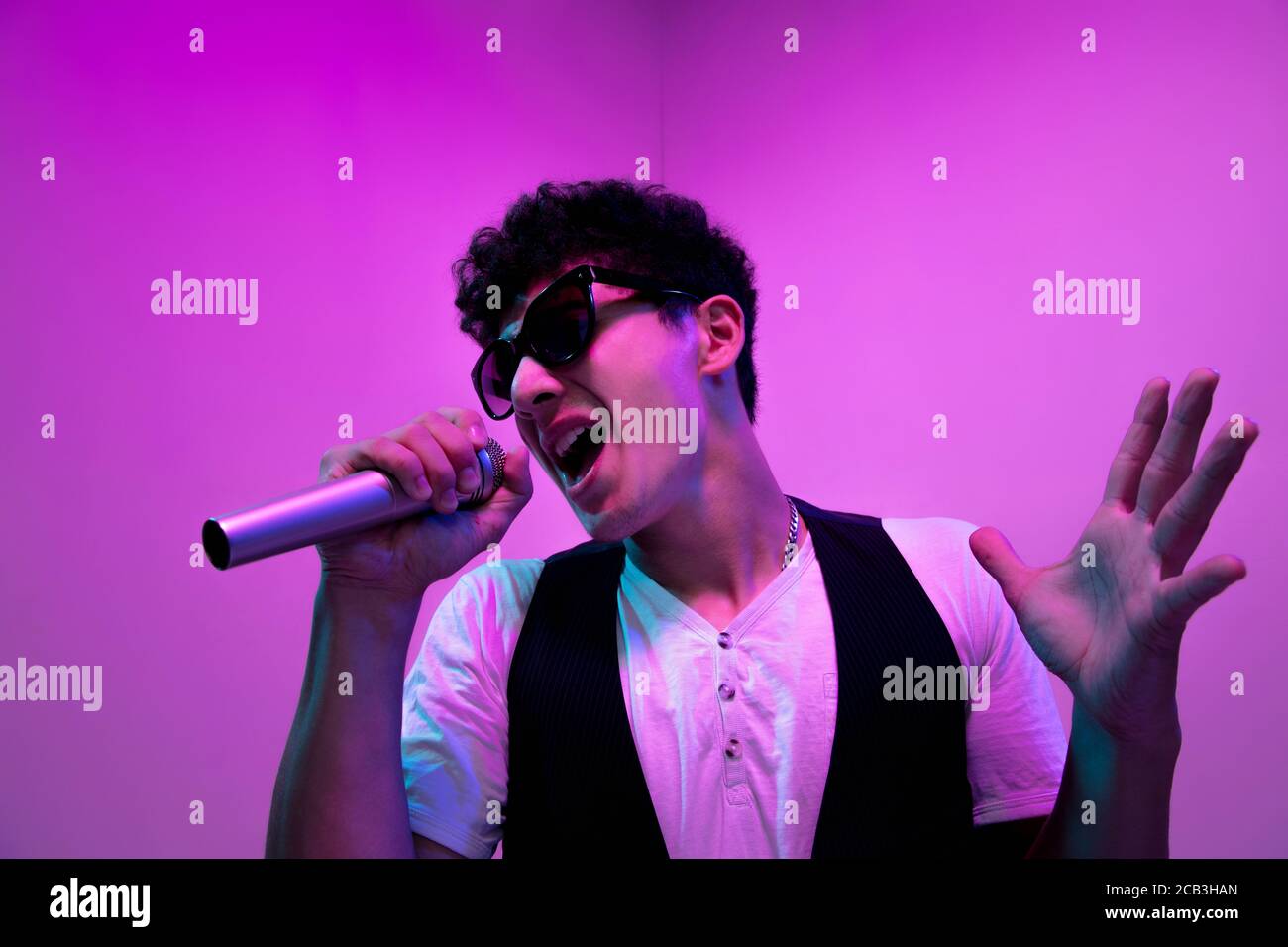 Summertime. Young male musician, singer performing on pink background ...