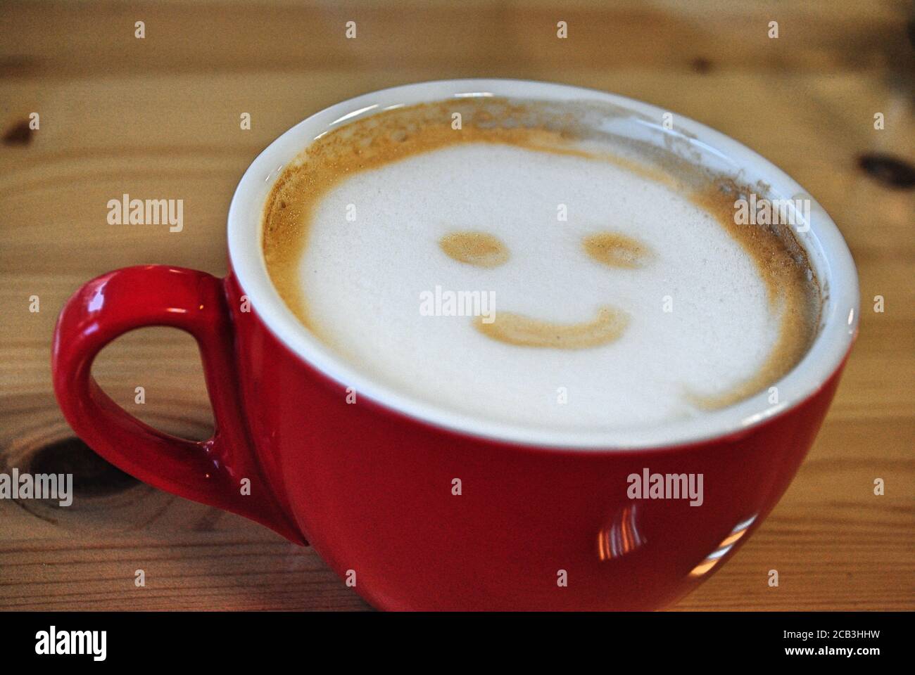 Red cup of Latte coffee with smiling face drawing in foam for left ...