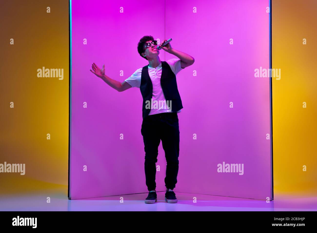 Inspired. Young male musician, singer performing on pink-orange ...