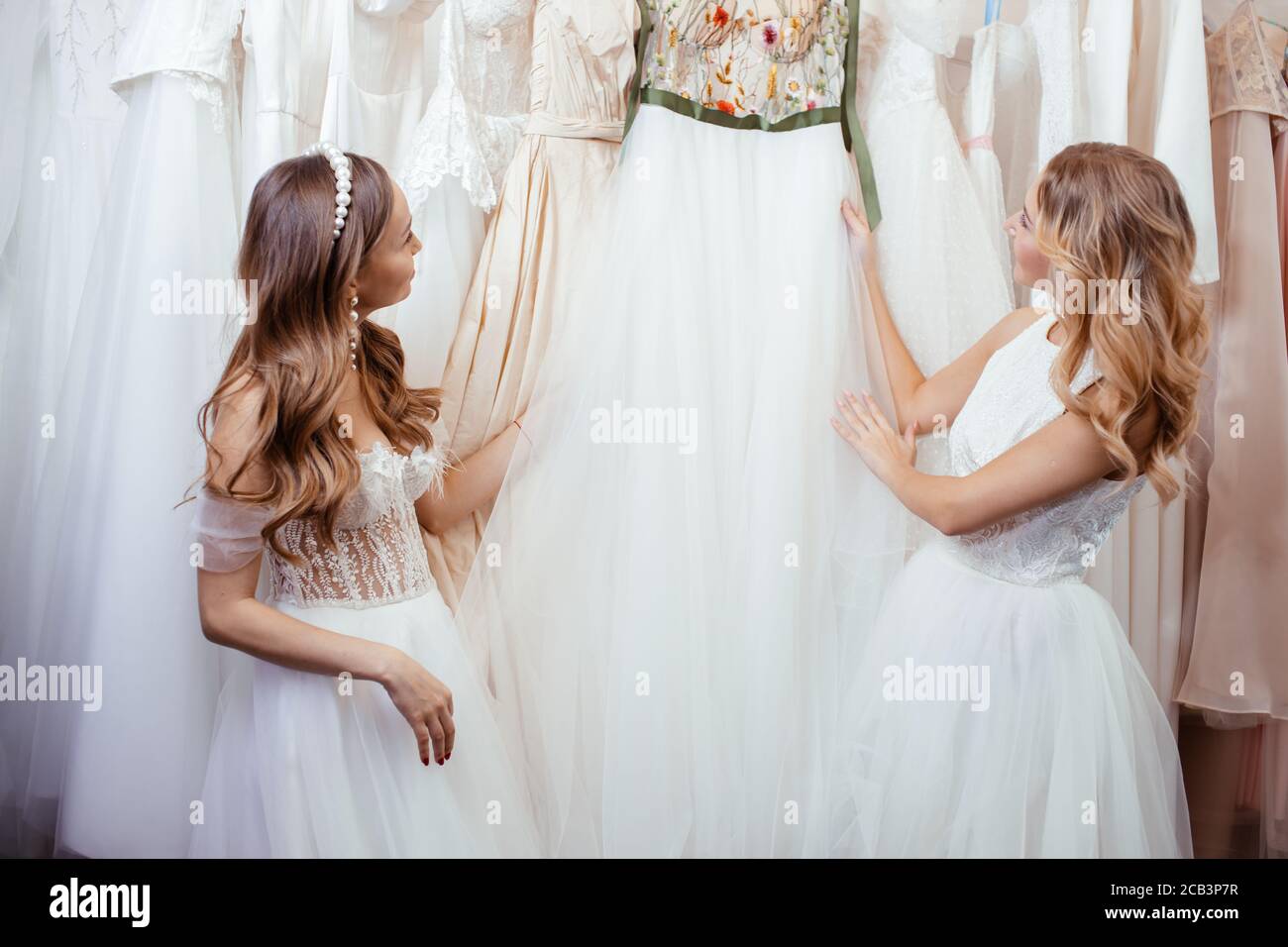 two young caucasian women choosing dress for wedding together, full ...