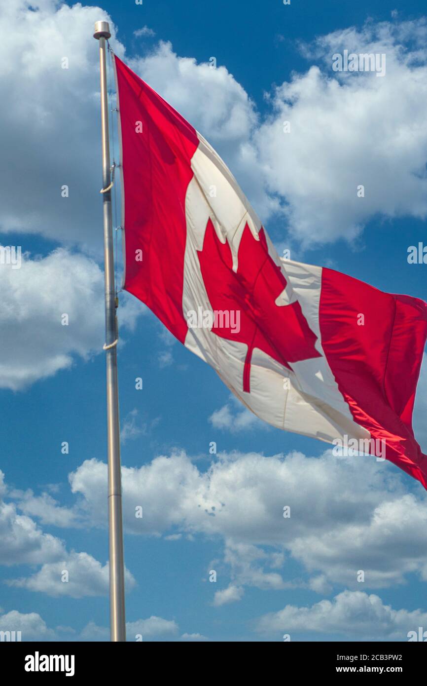 Maple leaf Flag of Canada against a background of blue sky with clouds ...