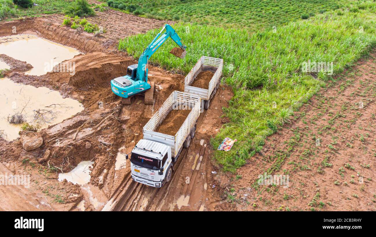 Backhoe loading soil into a truck then the truck carries soil for sale ...