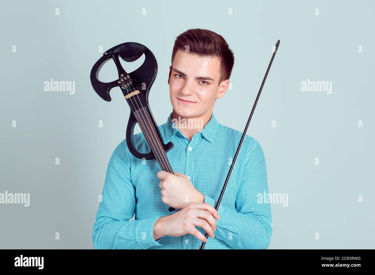 Young man posing holding modern violin and arc smiling crossing arms in ...