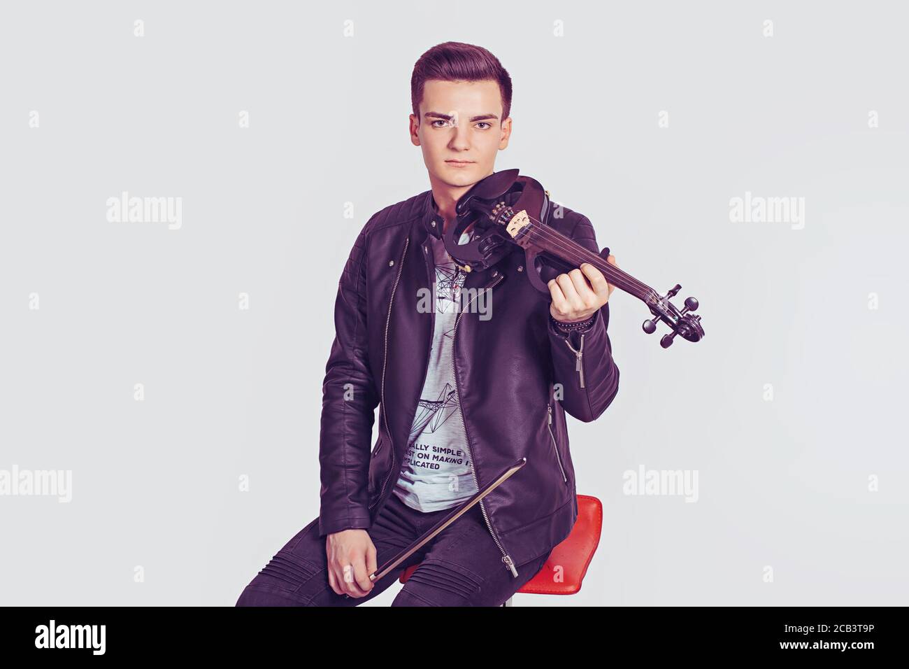 Young man posing holding modern violin and fiddle-stick smiling sitting ...