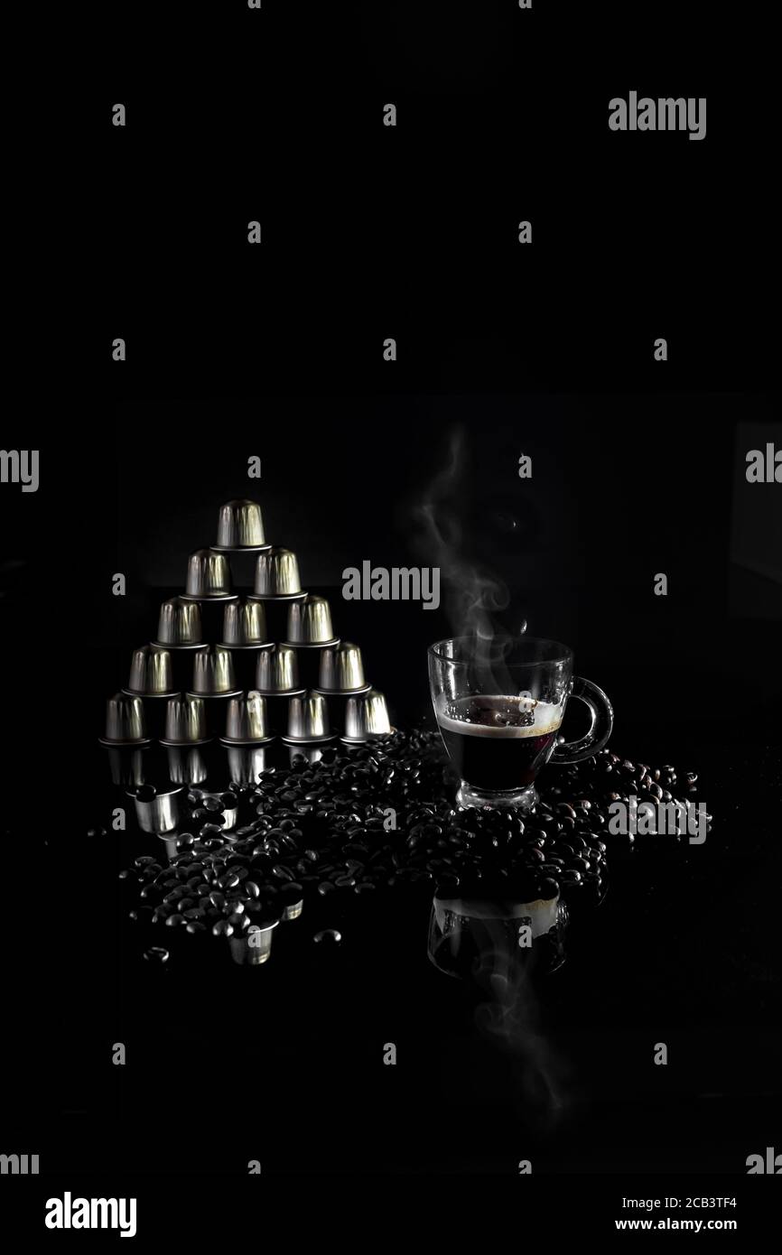 Vertical shot of a hot coffee with coffee capsule pyramid and beans ...