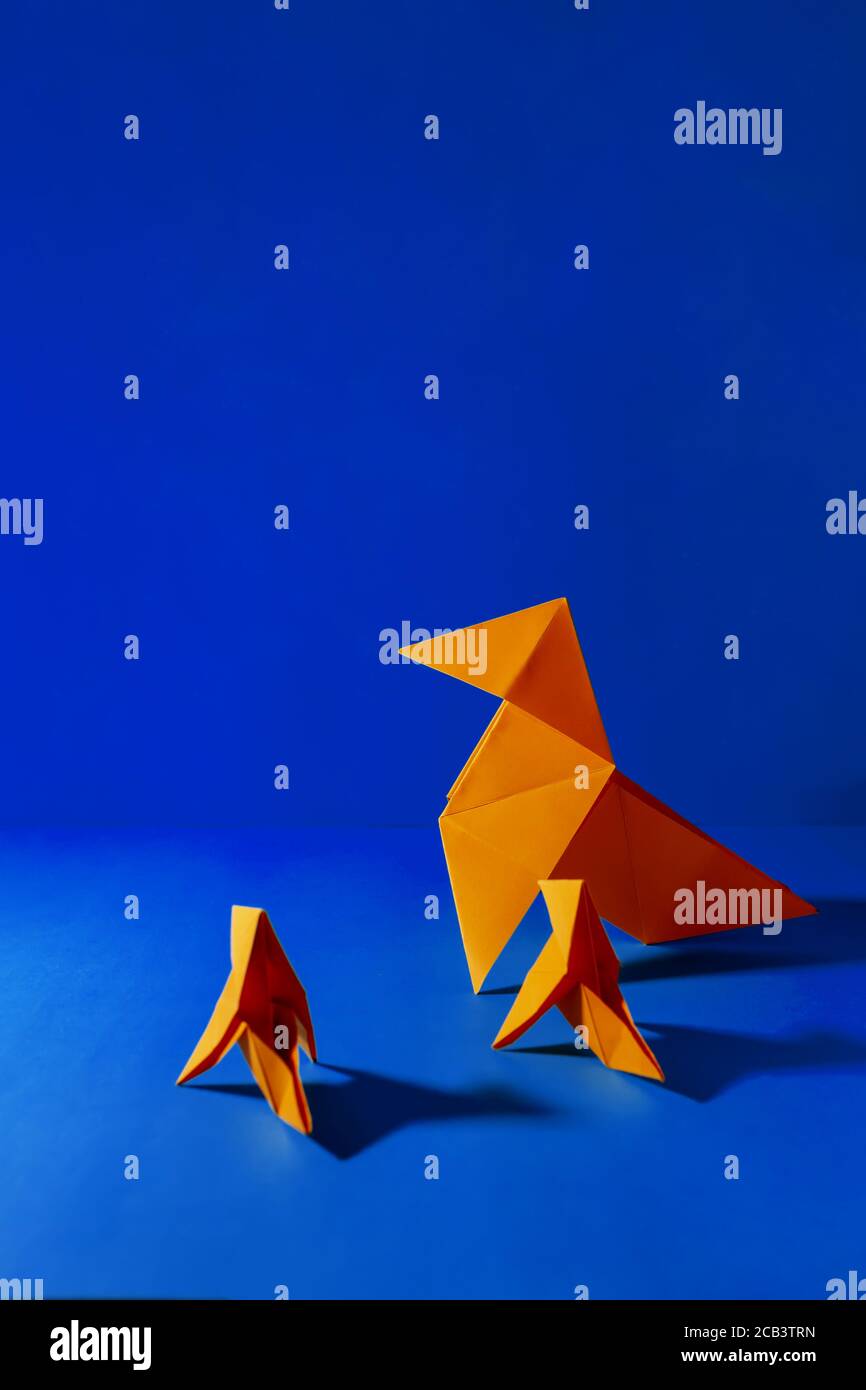 Vertical shot of an origami figures family isolated on a blue ...