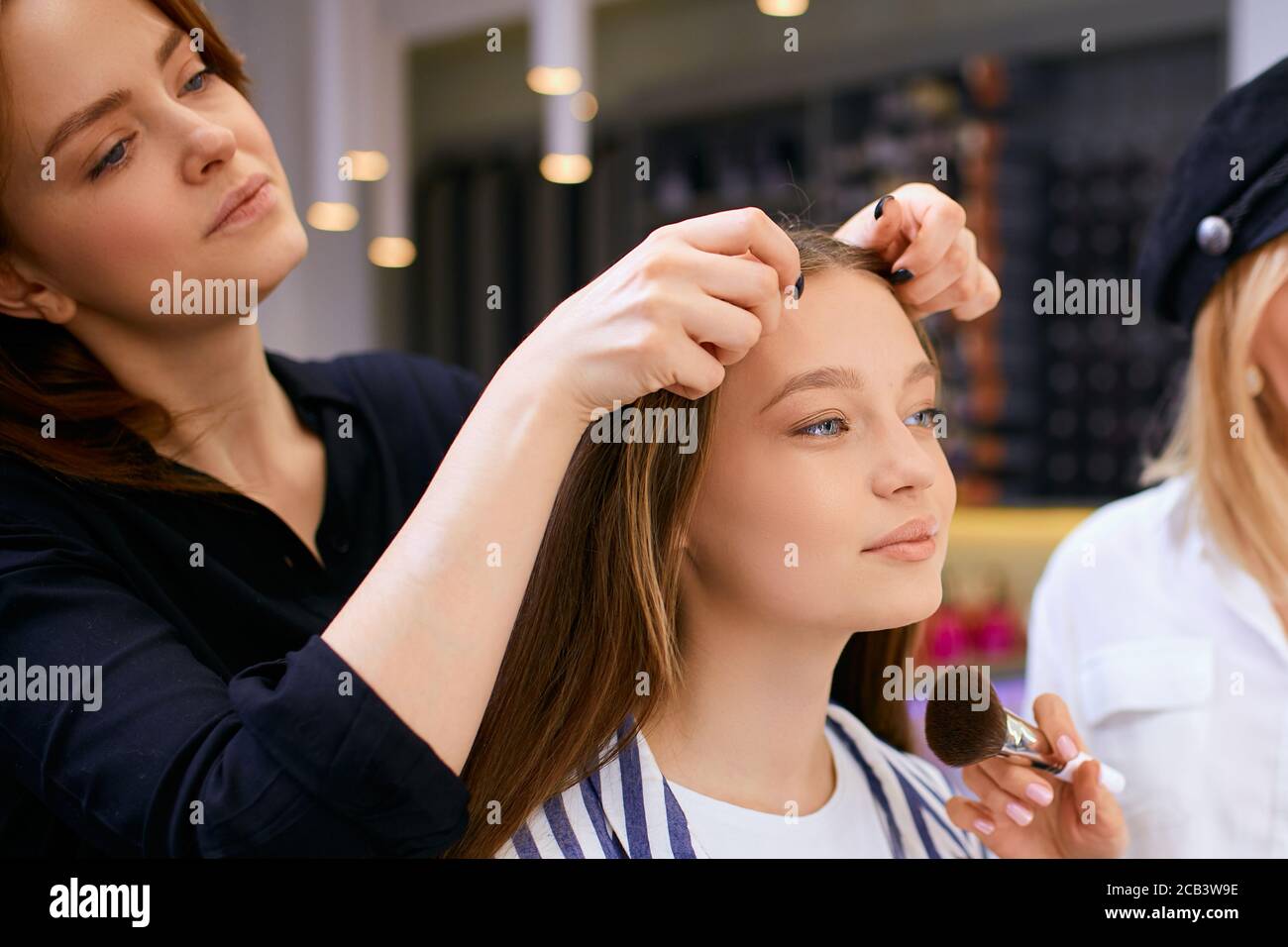 careful caucasian hairdresser holding client's hair in hands, going to ...