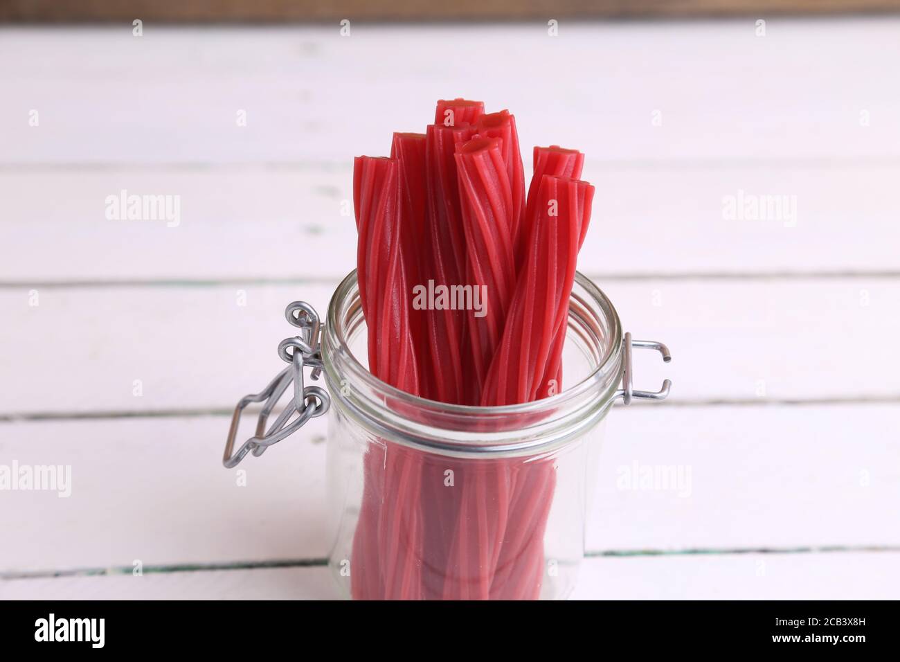 High angle shot of a container filled with red stick candies on a white ...