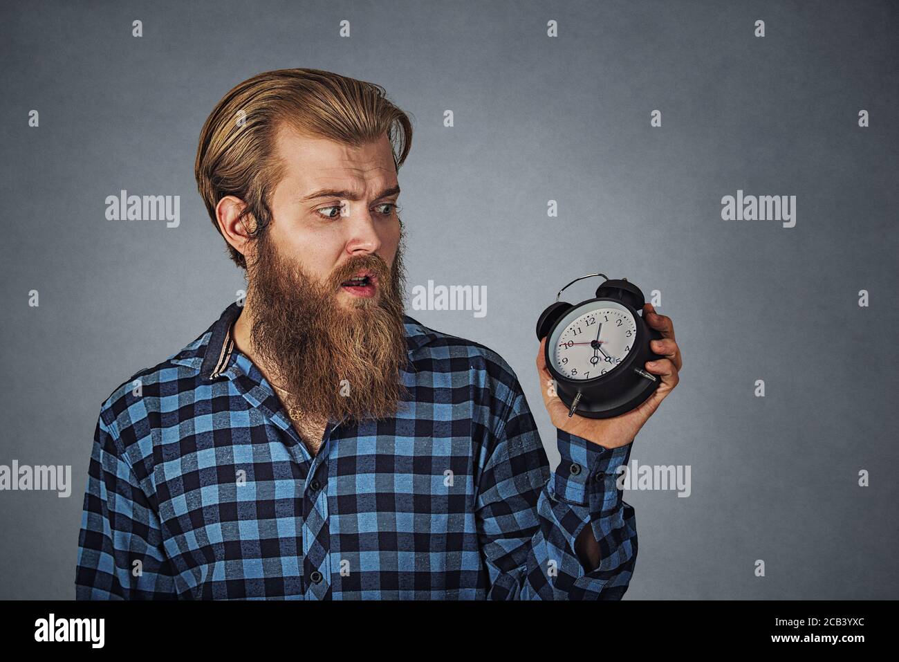 Young shocked man looking at alarm clock with fear being late. Hipster ...