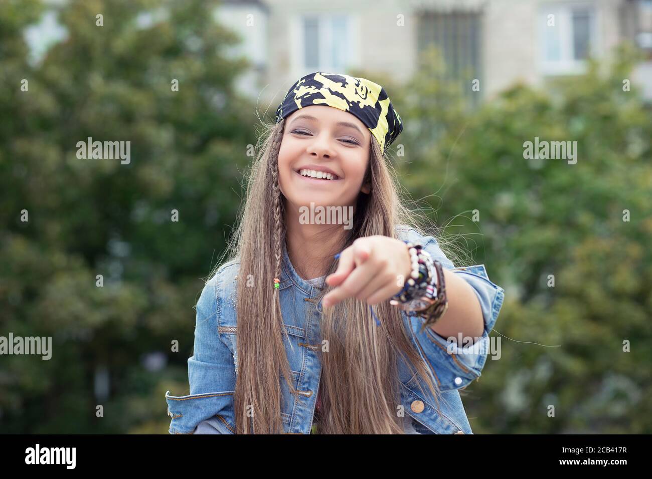 Laughing young rebel woman pointing at camera and laughing cheerfully ...