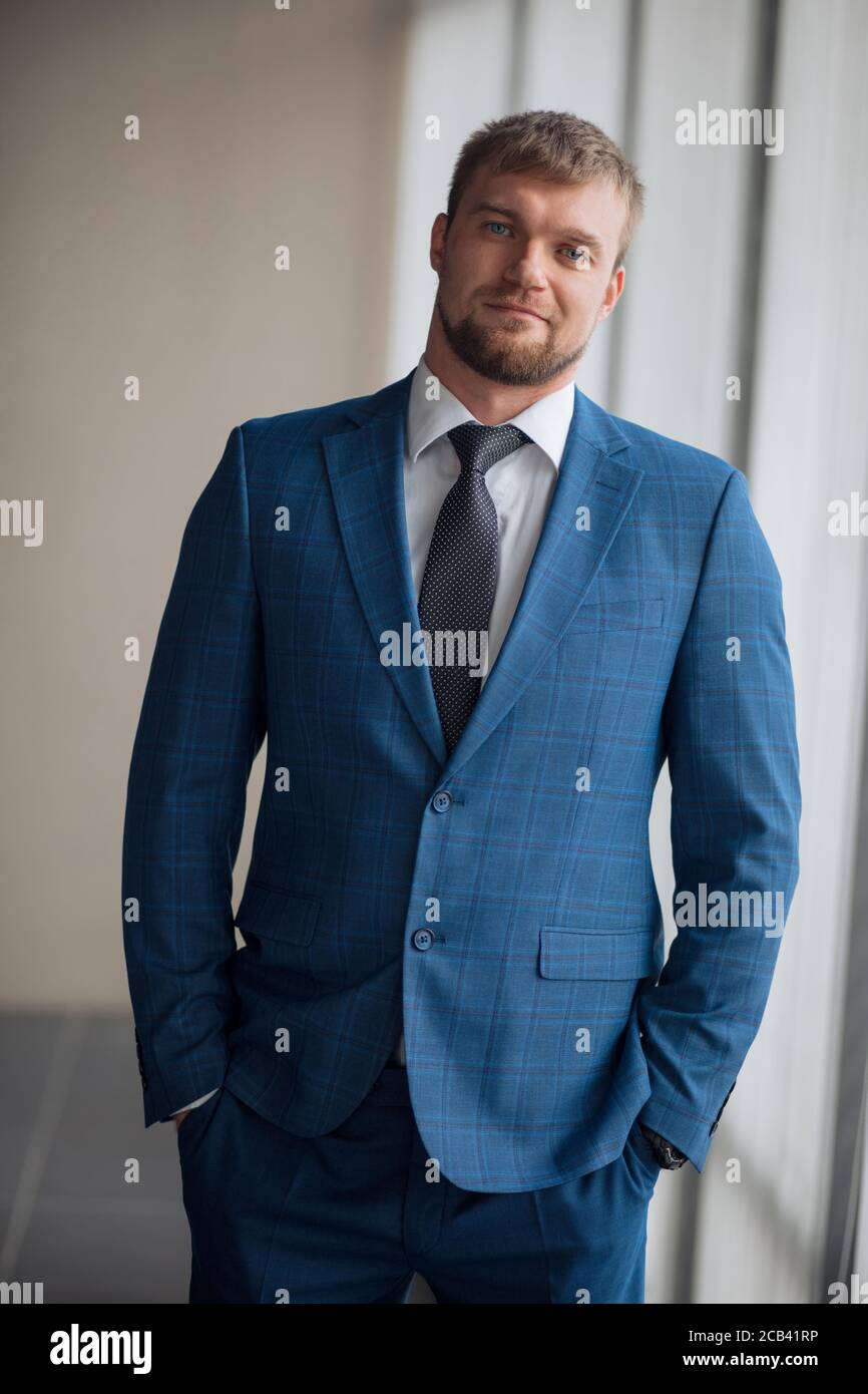 confident fair-haired CEO with blue beautiful eyes looking at the ...