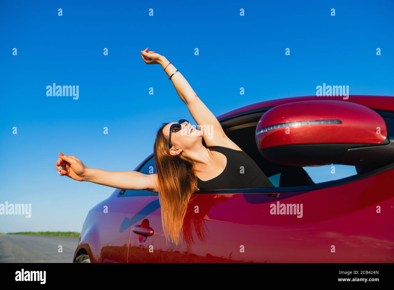 Happy young female enjoy road trip, out half body from open auto window ...