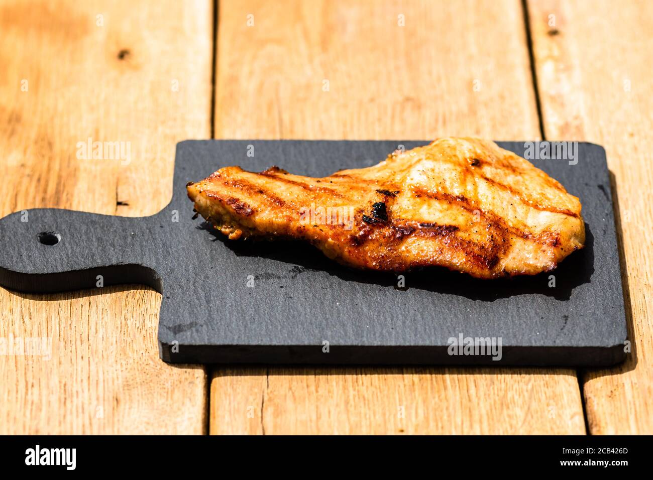 Close up of grilled steak on small black chopping board isolated ...