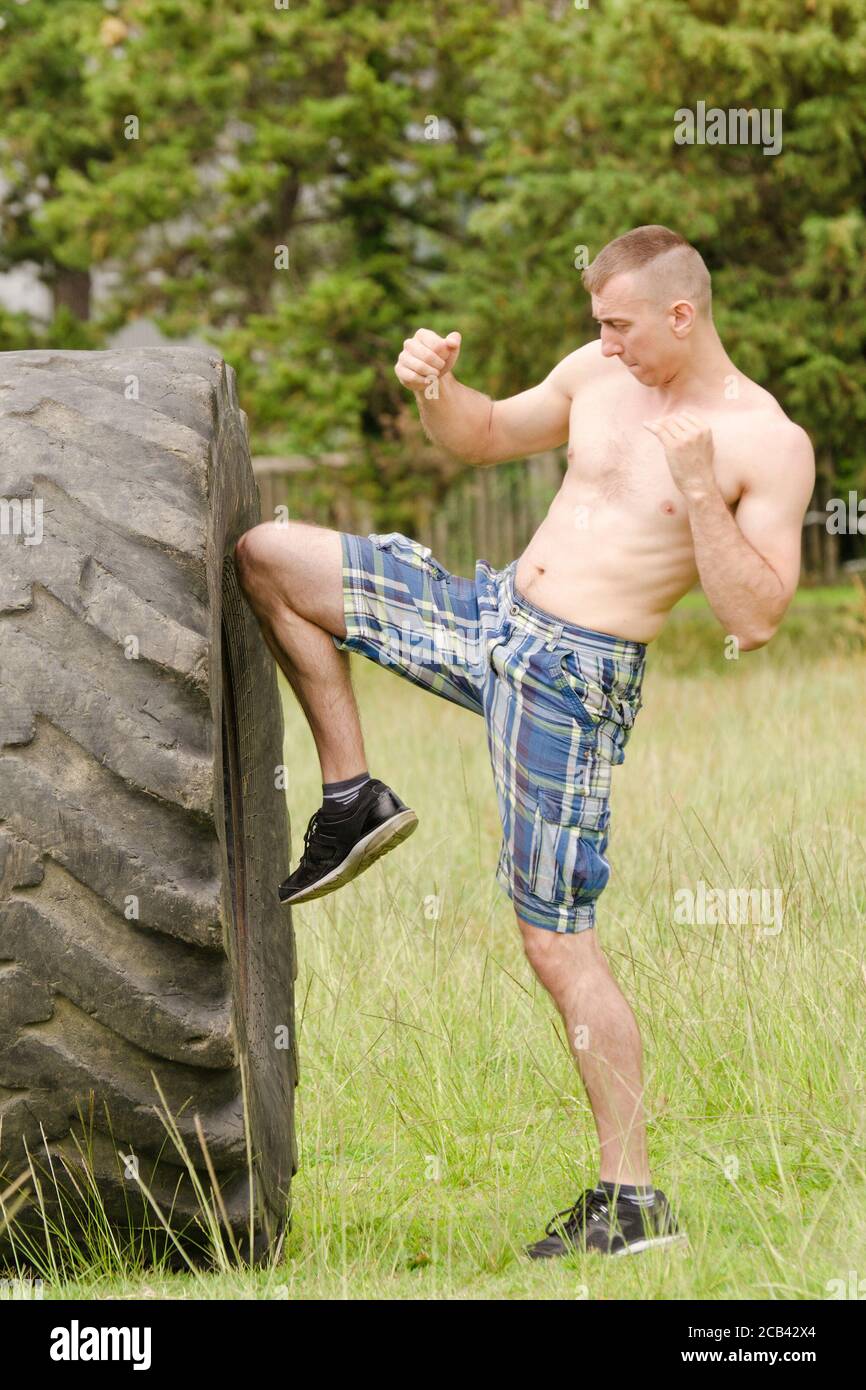 Young man is kicked a foot in a tire. Workout Stock Photo - Alamy