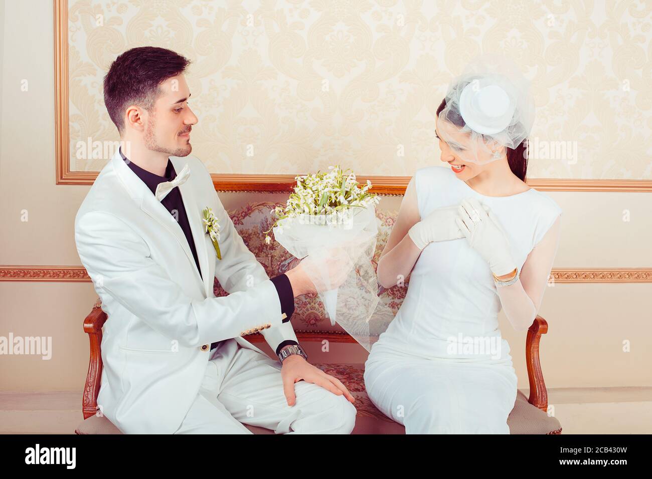 Modern classy groom giving floral bouquet to excited young bride in ...