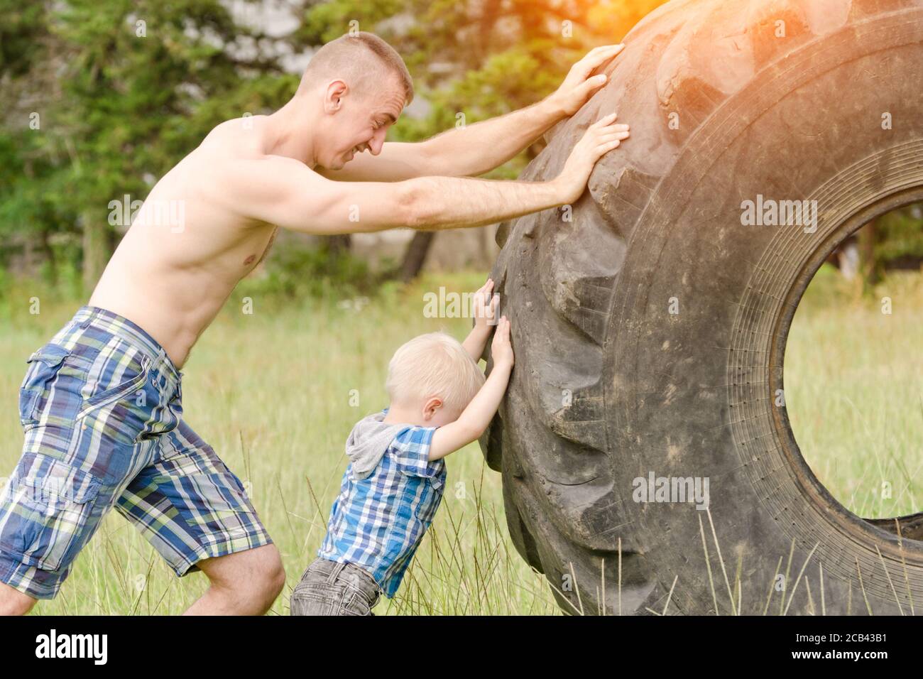 Dad and son push a big tire. Street workout Stock Photo - Alamy