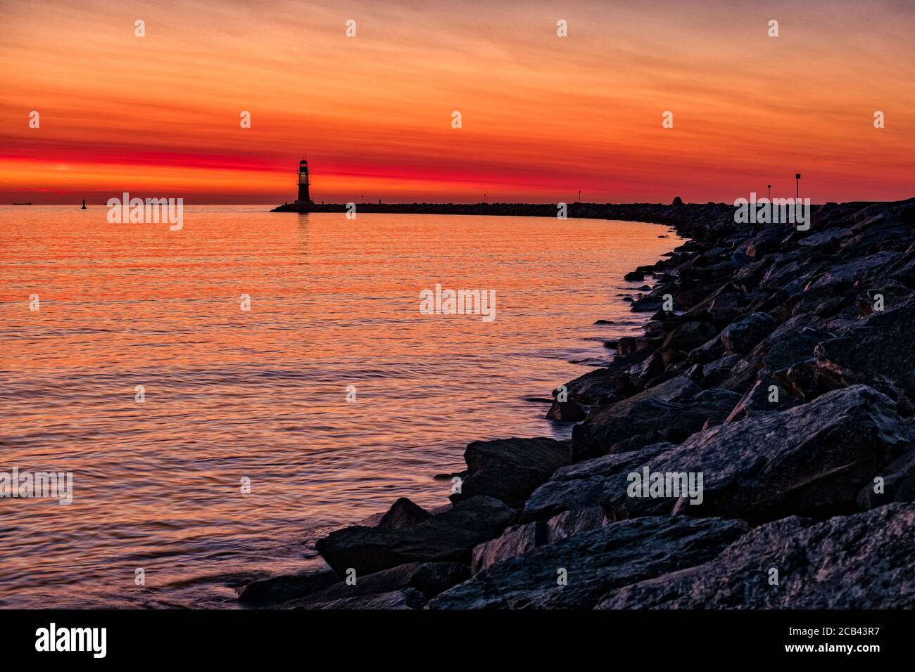 The sun is setting behind the lighthouse of the suburb Hohe Düne Stock ...