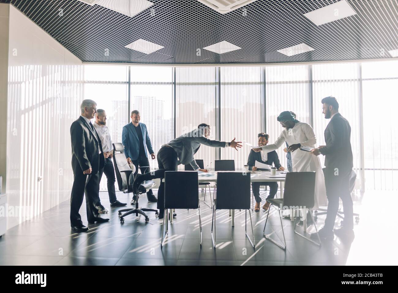 Ironic shot of caucasian businessman climbs over the office desk on his ...