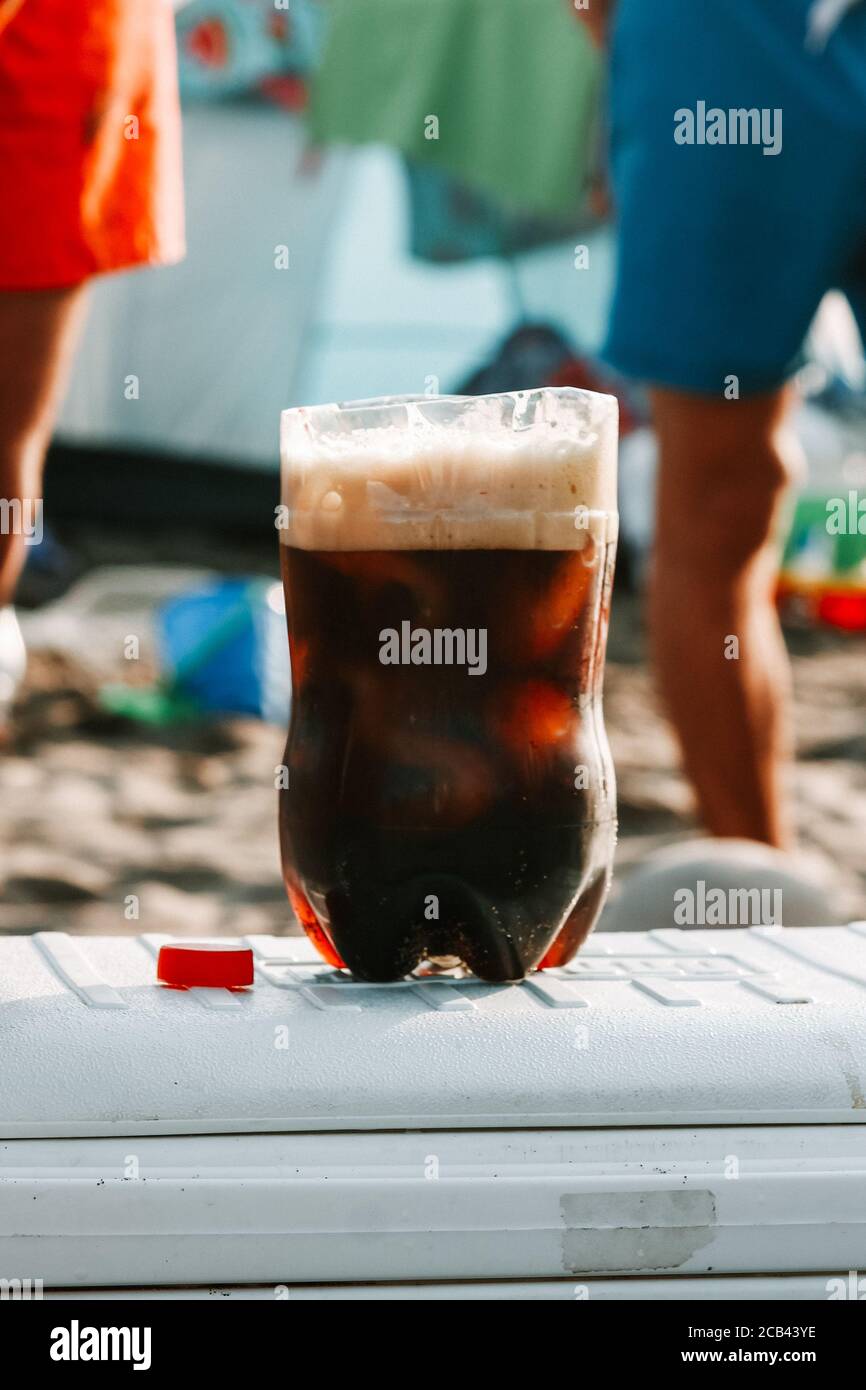 Vertical shot of a half-cut plastic bottle serving as a cup filled with ...