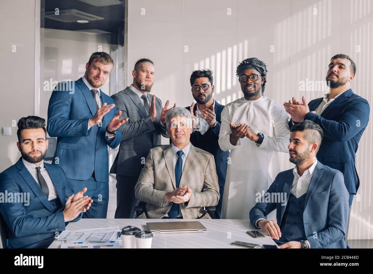 Diverse smiling business men gather at conference table together with ...