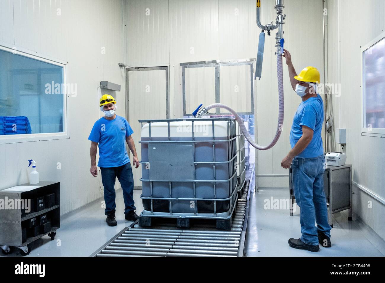 Workers fill vats with organic agave syrup at the IMAG distillation ...