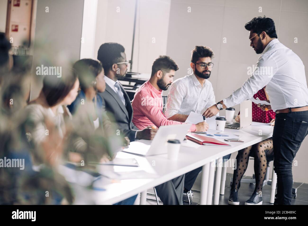 Indian man handing out paper tests to his international co-workers ...