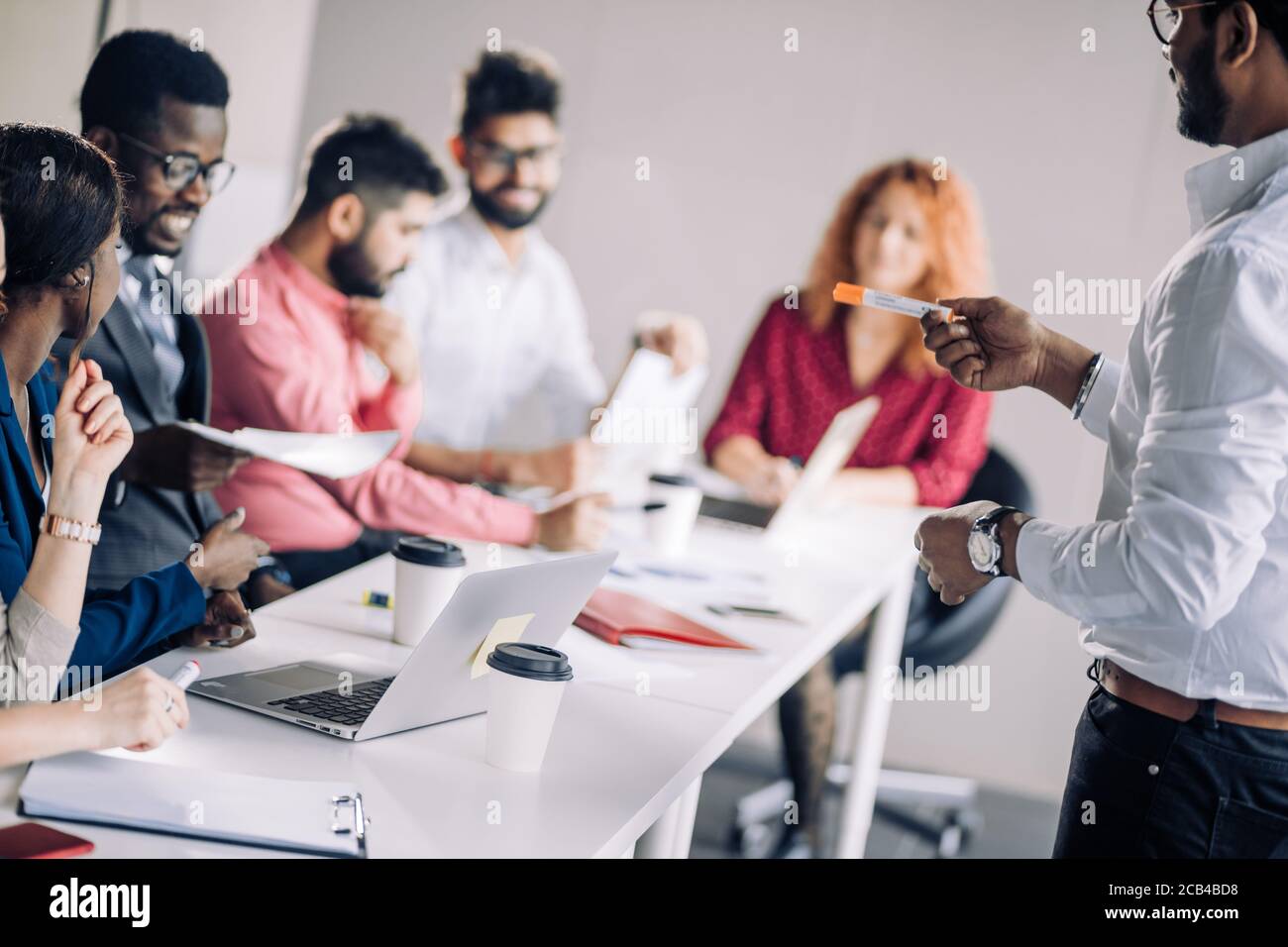Indian man handing out paper tests to his international co-workers ...