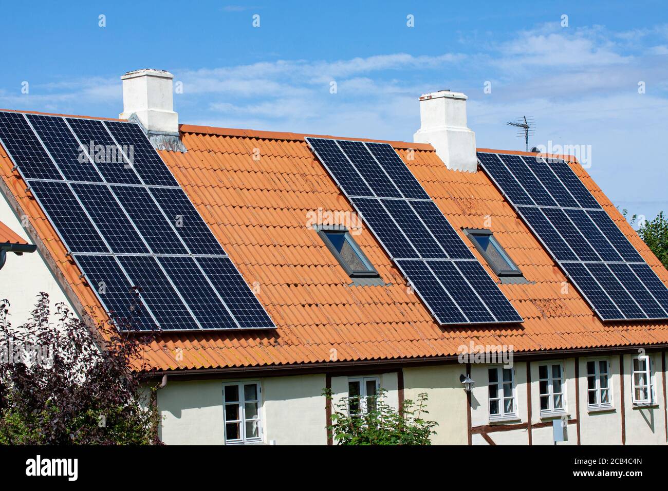 Modern black solar panels on the red tile roof of an old house with ...